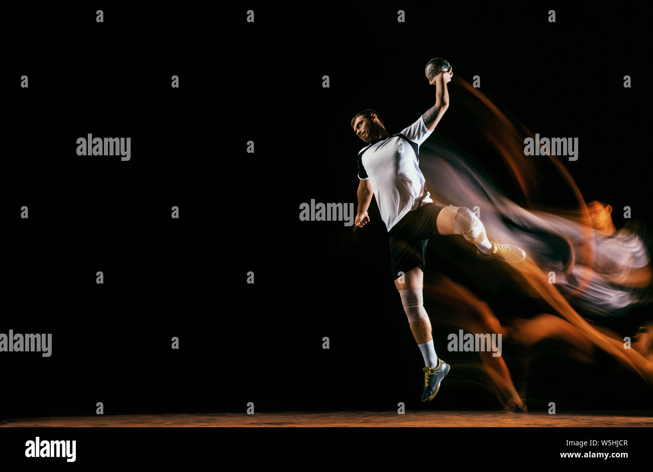 Caucasian young handball player in action and motion in mixed lights ...