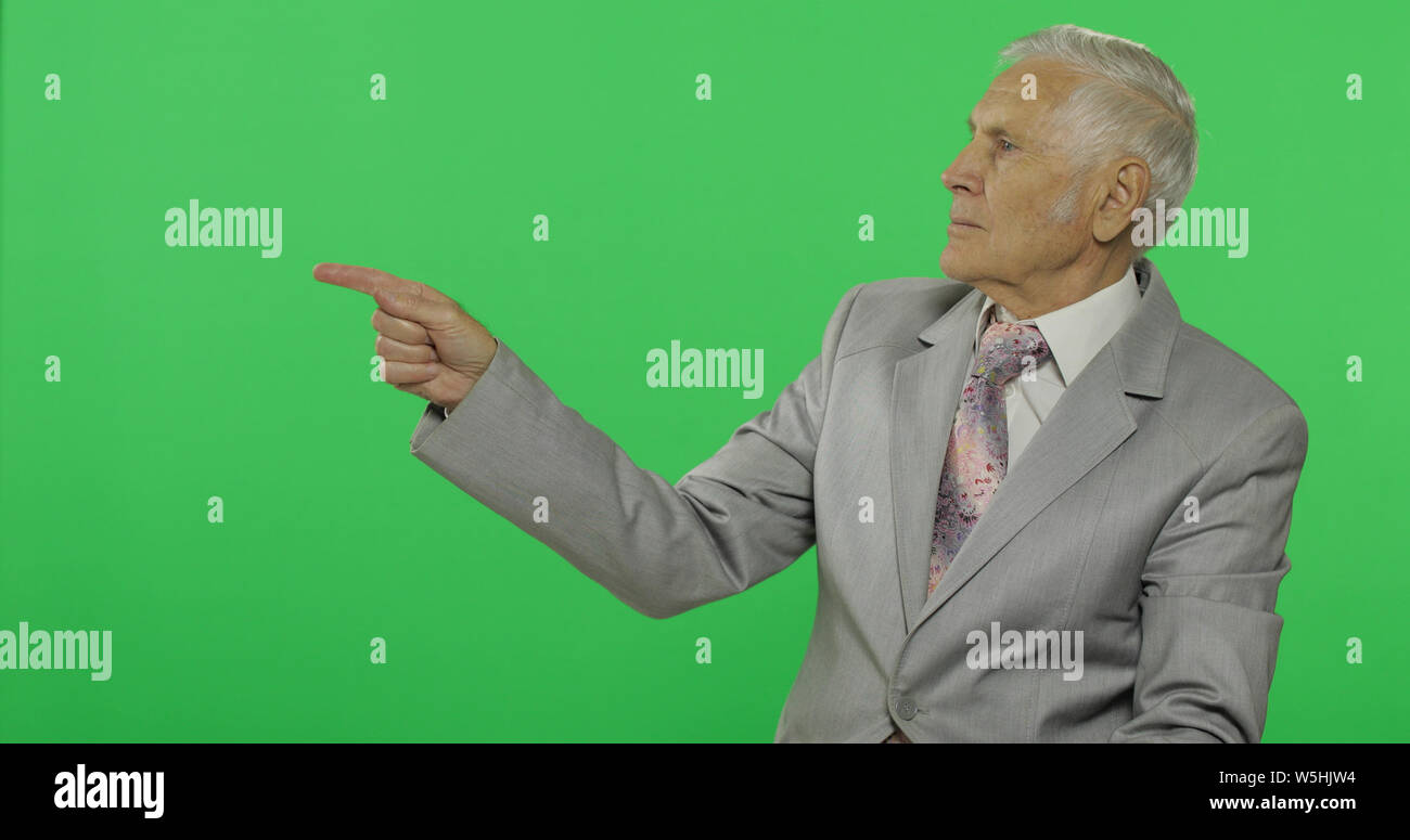 Elderly businessman points at something. Old man in formal wear showing ...