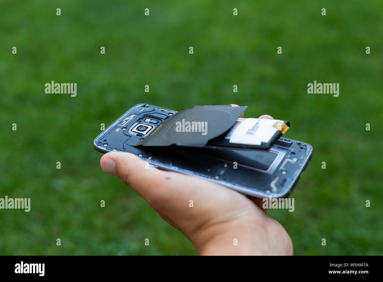 Close up of a damaged smartphone with expanded lithium ion battery ...