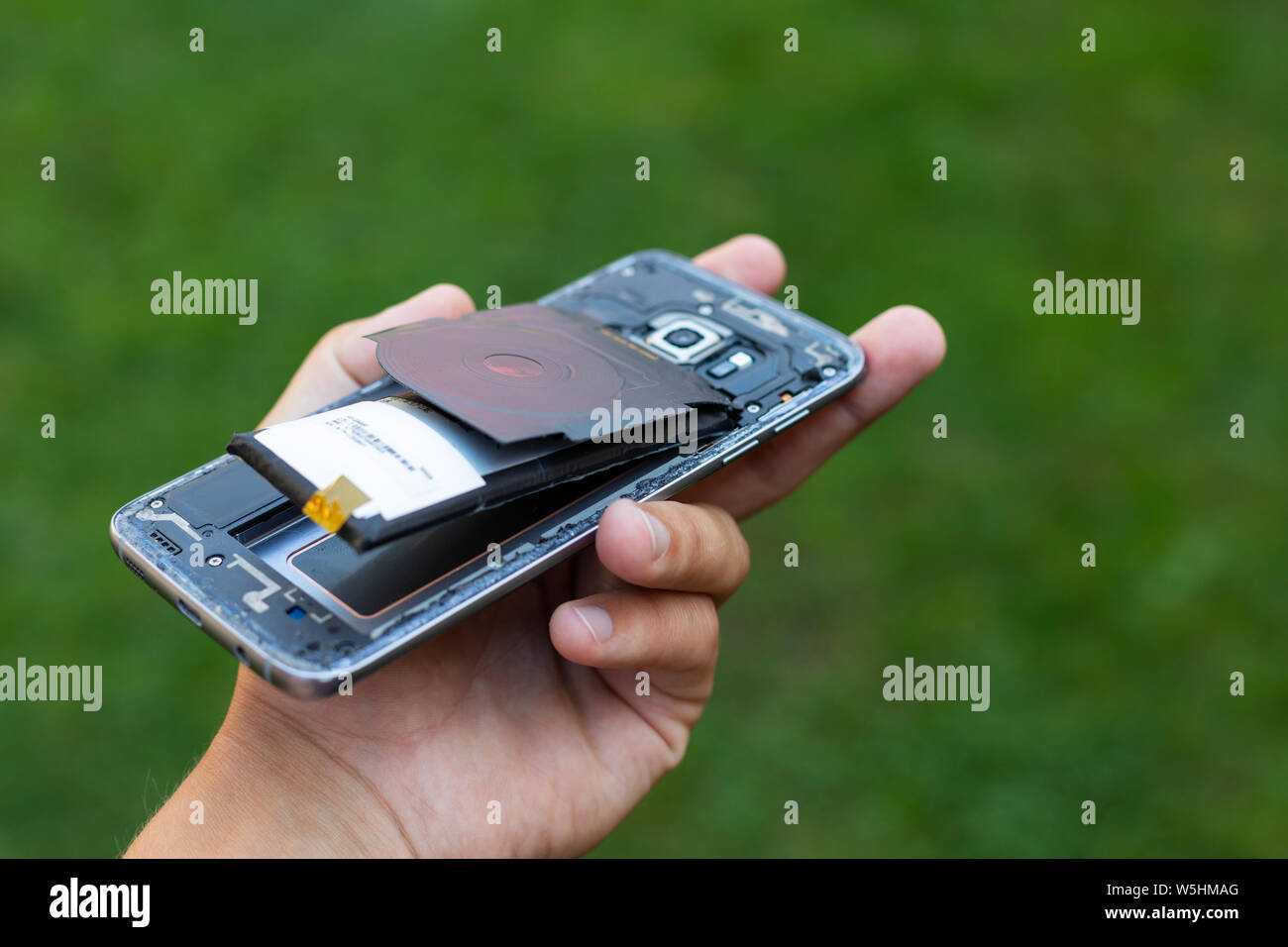 Close up of a damaged smartphone with expanded lithium ion battery ...