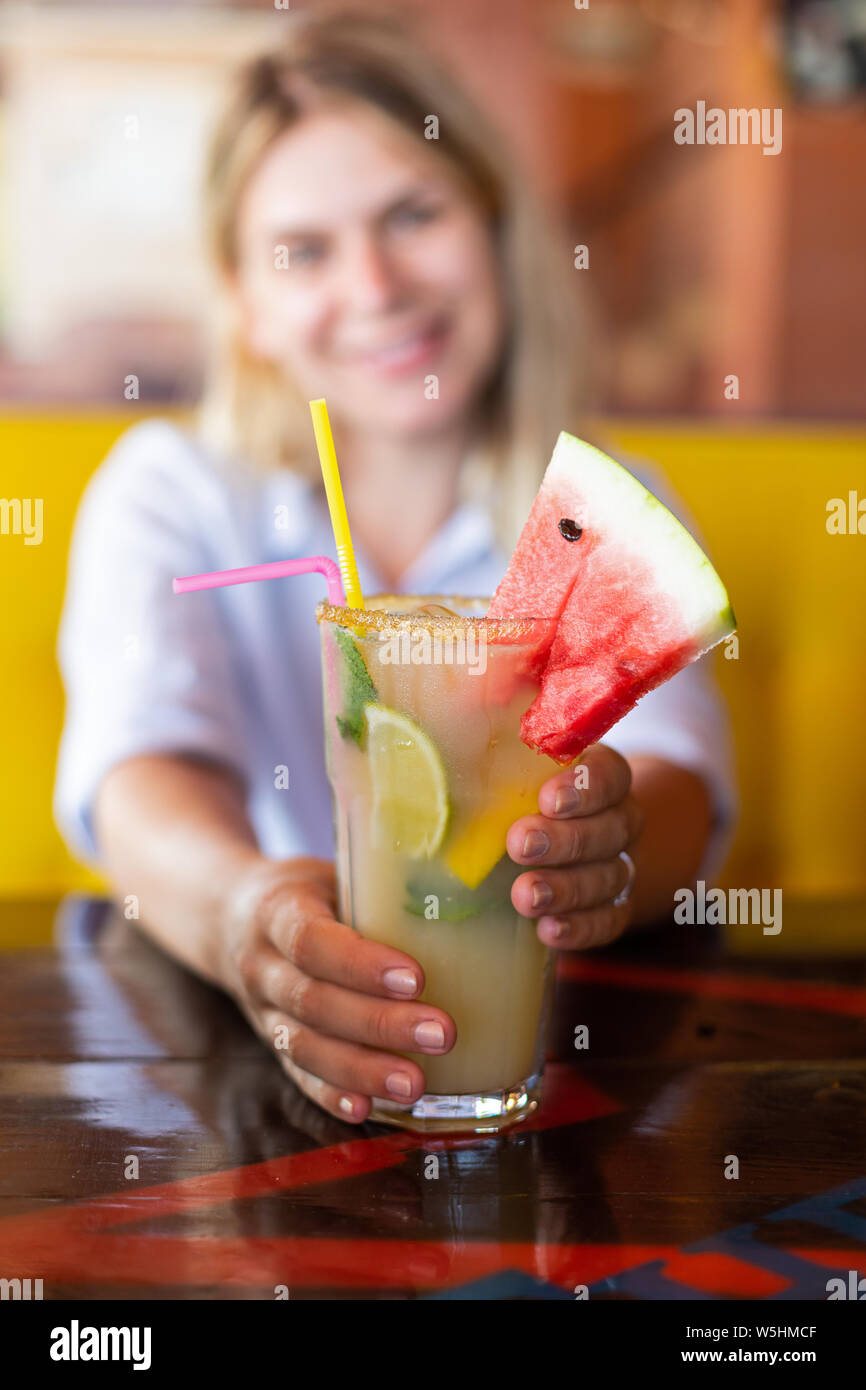 Woman holding a cold refreshing lemonade at a beach terrace on a hot ...