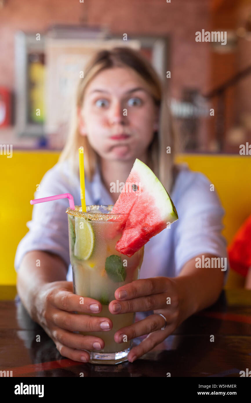 Woman holding a cold refreshing lemonade at a beach terrace on a hot ...