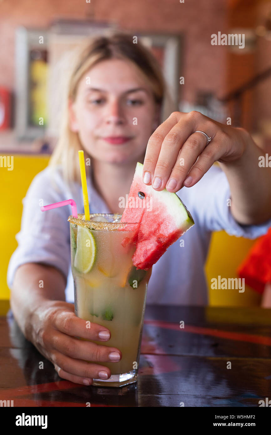 Woman holding a cold refreshing lemonade at a beach terrace on a hot ...