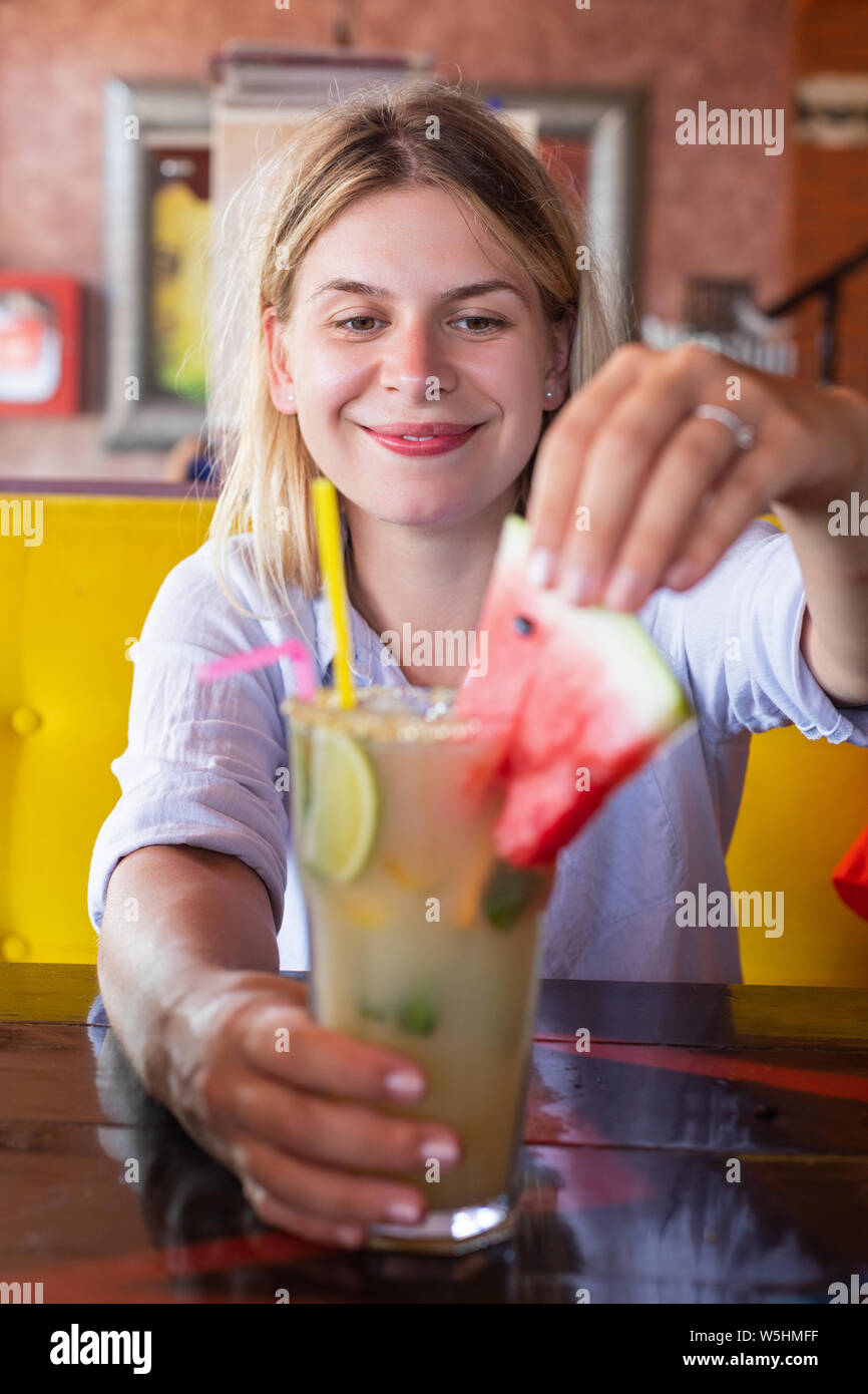 Woman holding a cold refreshing lemonade at a beach terrace on a hot ...