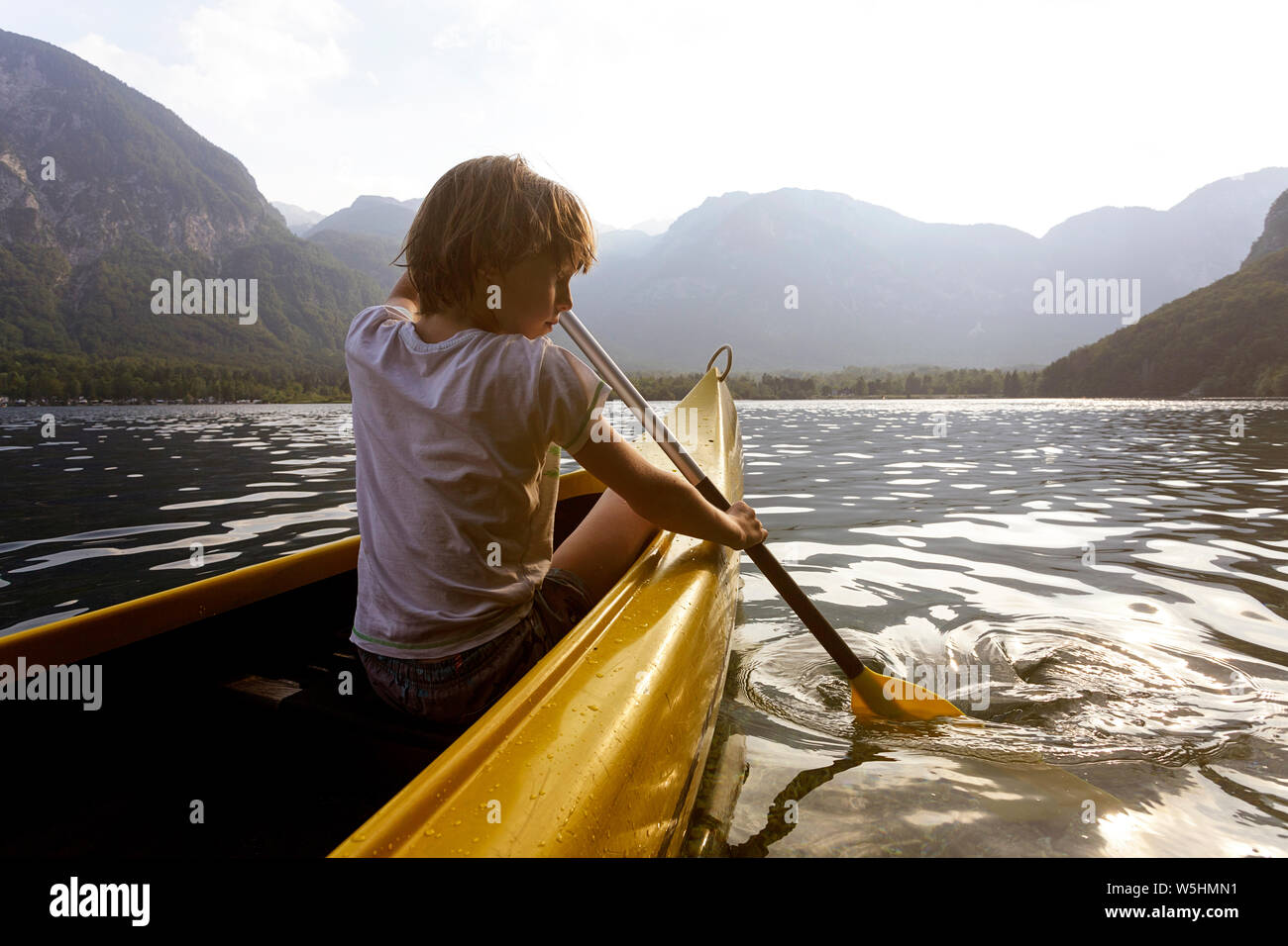 child in the front of a canoe paddling on the calm Bohinj lake ...
