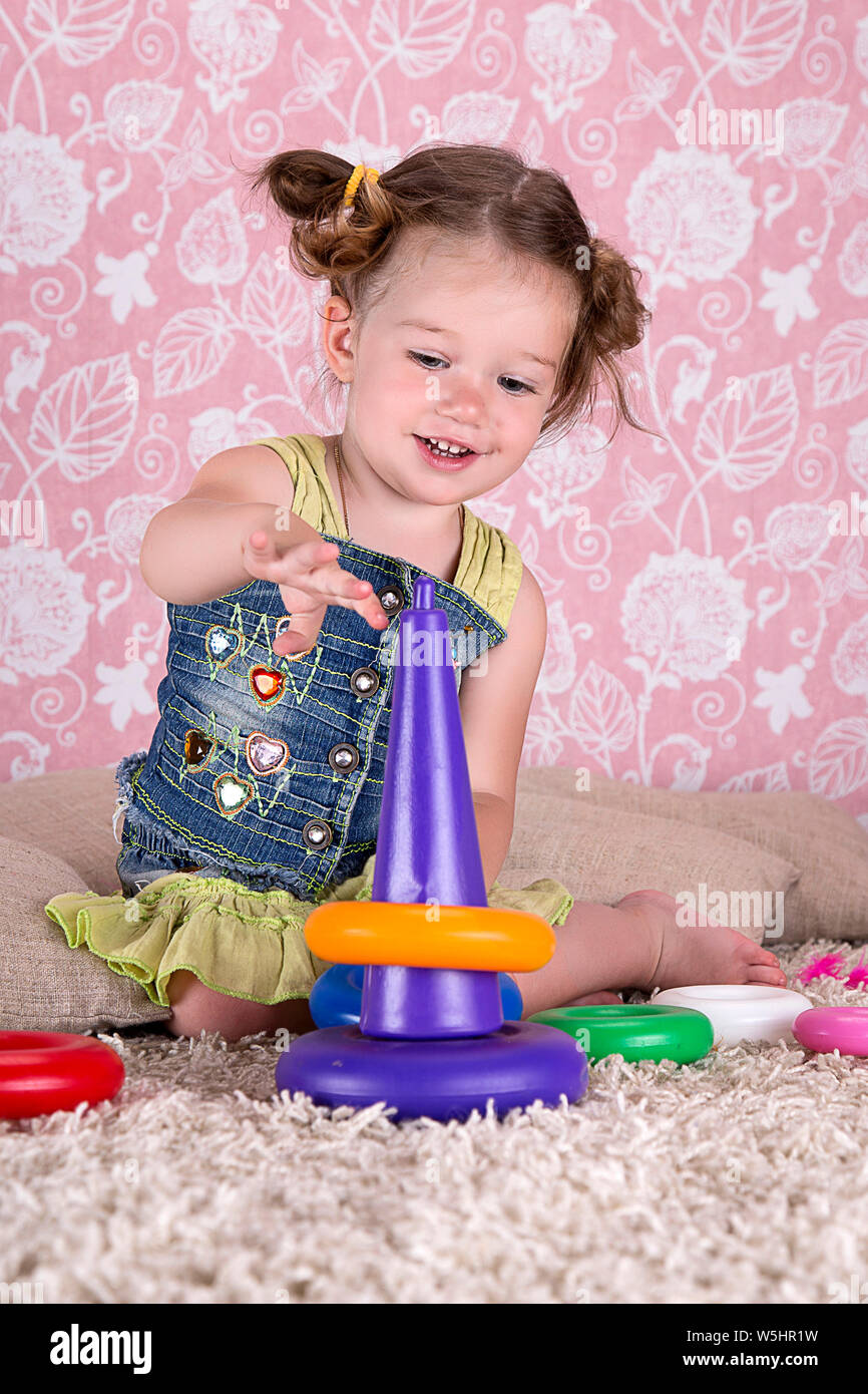 beautiful little girl plays plastic pyramid girl sitting on a white ...