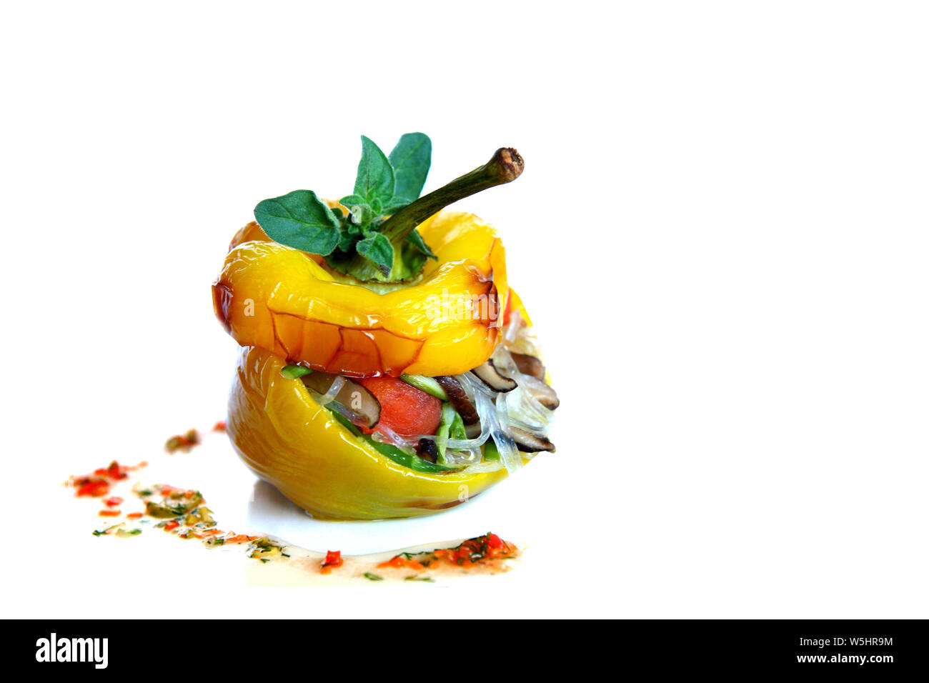 Cooked yellow pepper with vegetables inside on a white background with ...