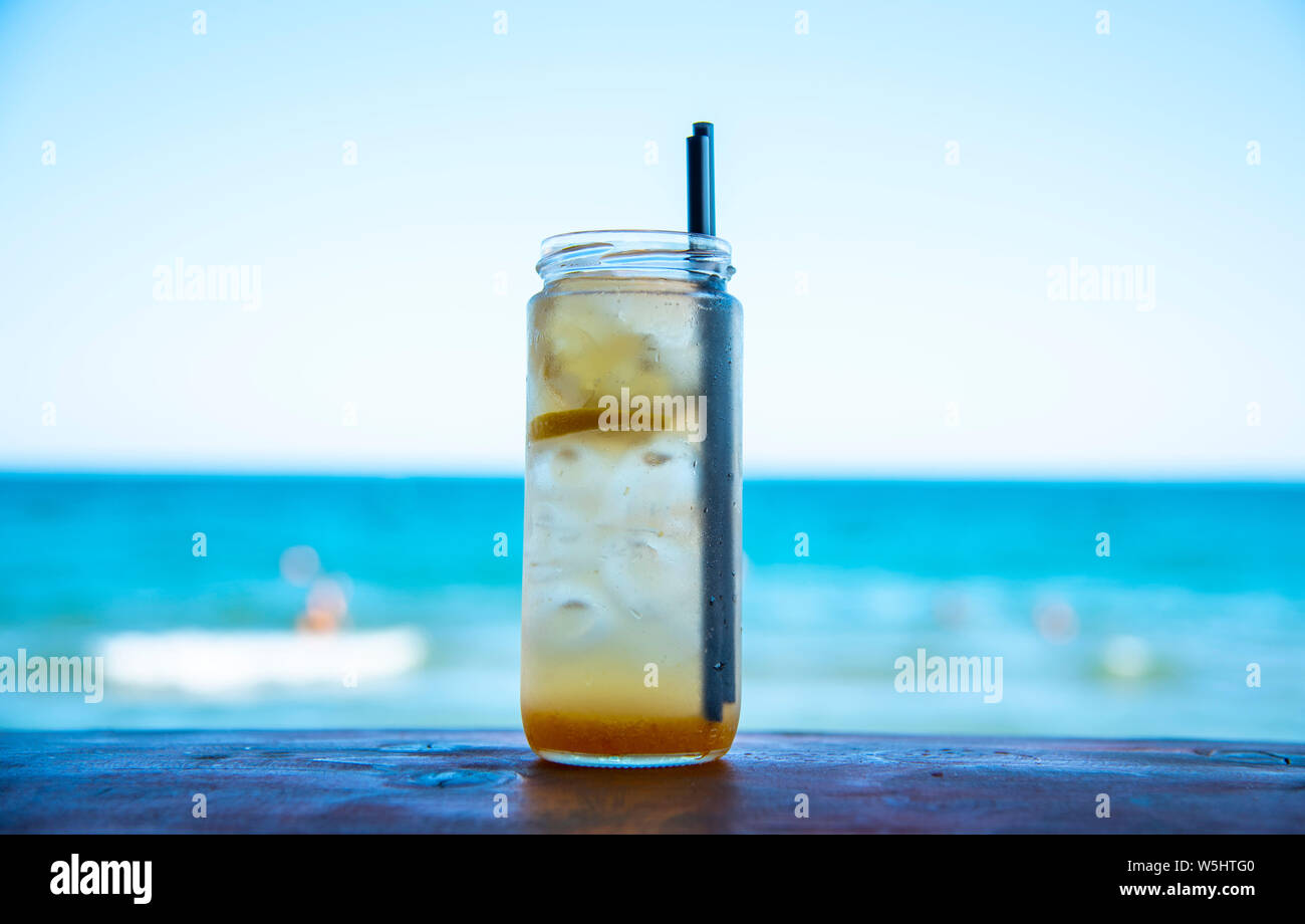 A jar of lemonade, in which float lemon and ice, with two black tubes ...