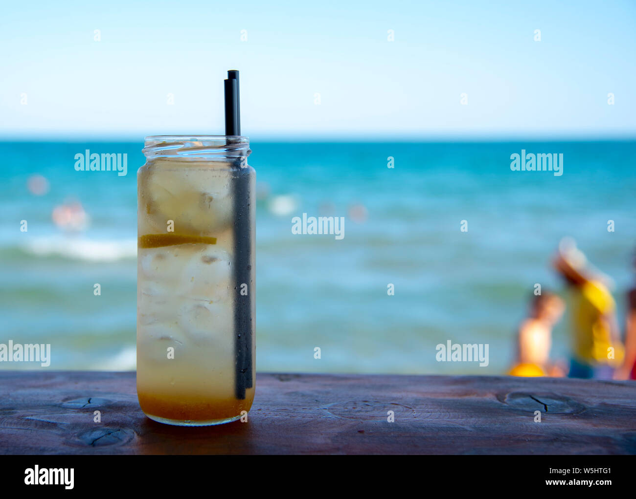 A jar of lemonade, in which float lemon and ice, with two black tubes ...