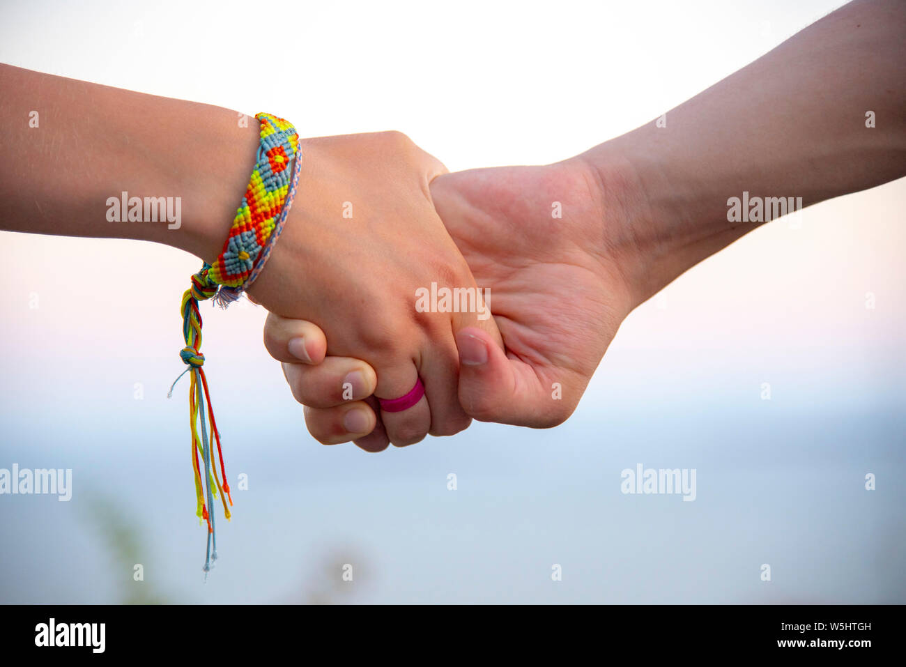 Two hands, male and female, holding each other tightly, on a blurred ...