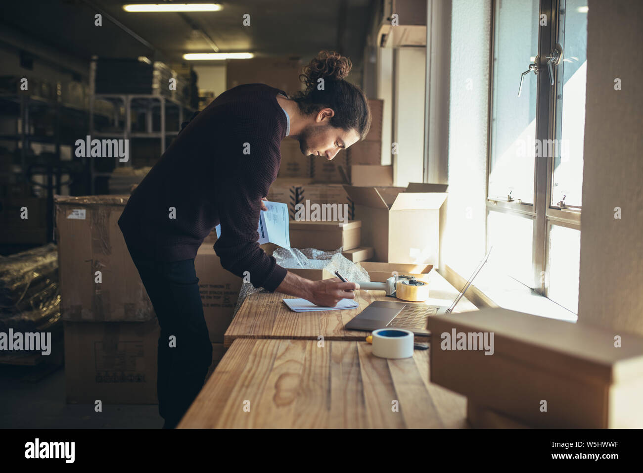 Man making note of the order he is packing to delivery. Young man ...
