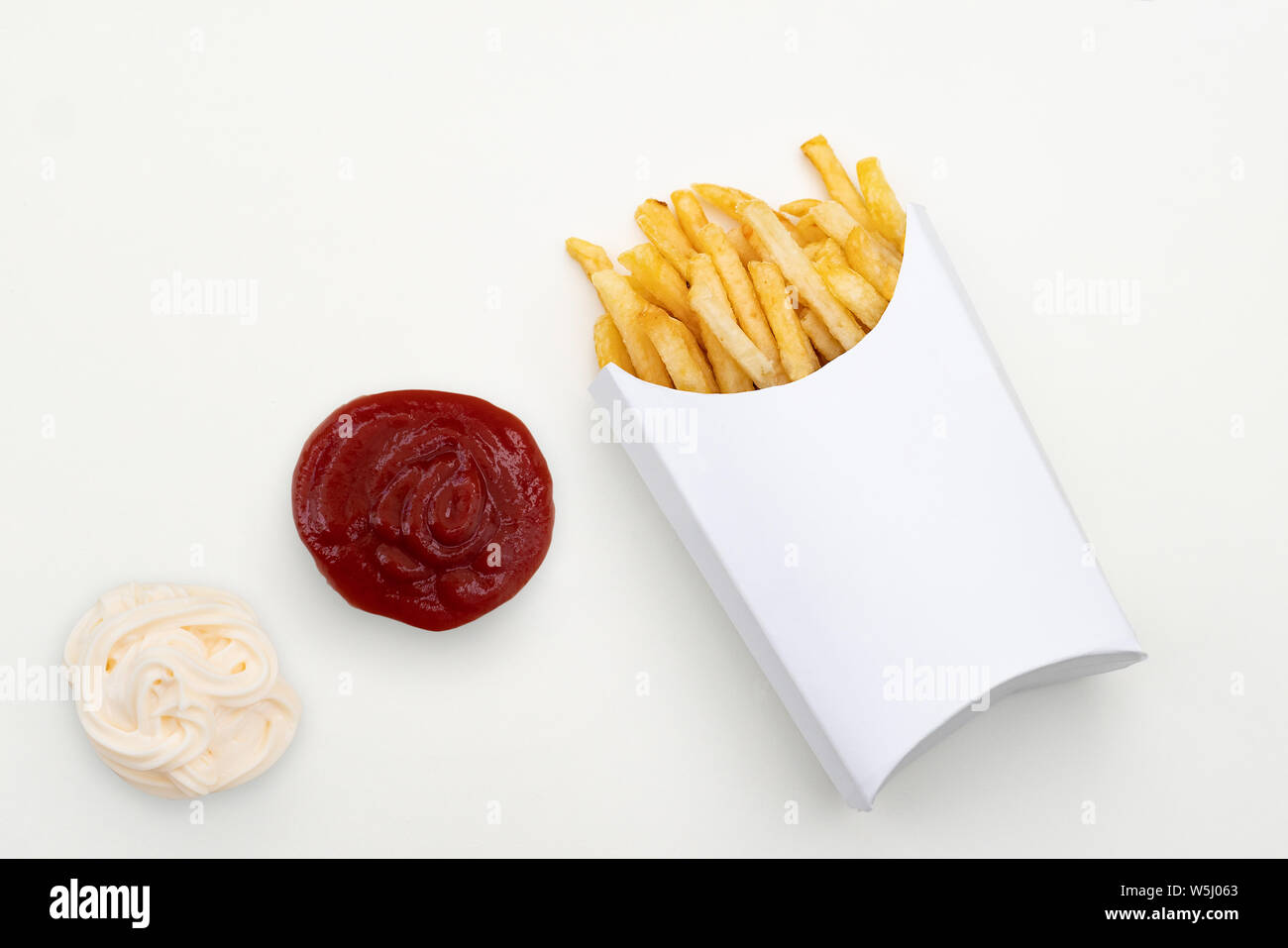 A portion of French fries in a white cardboard box. A blob of tomato ...