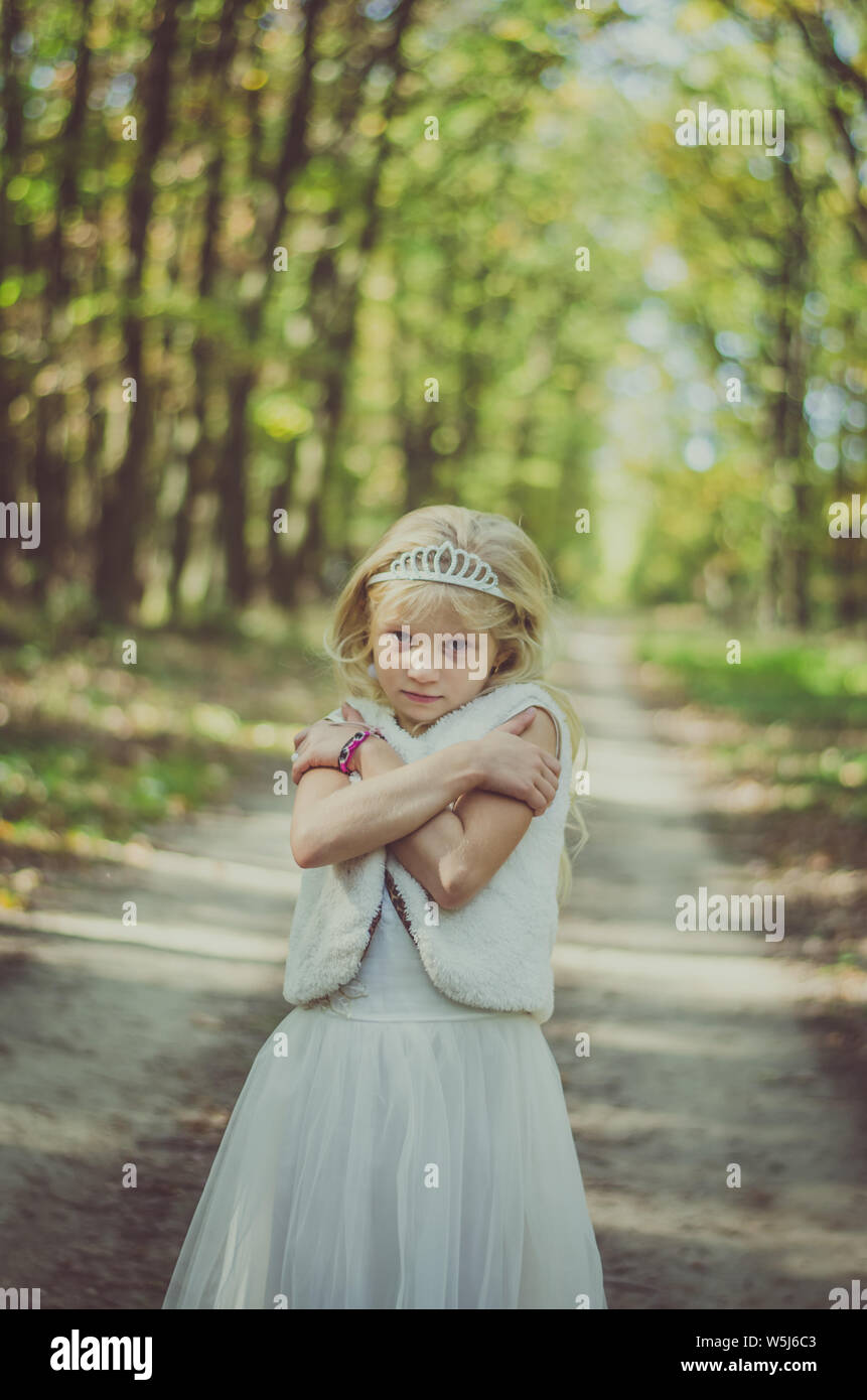 one little girl in dress freezing in path among autumnal trees in ...
