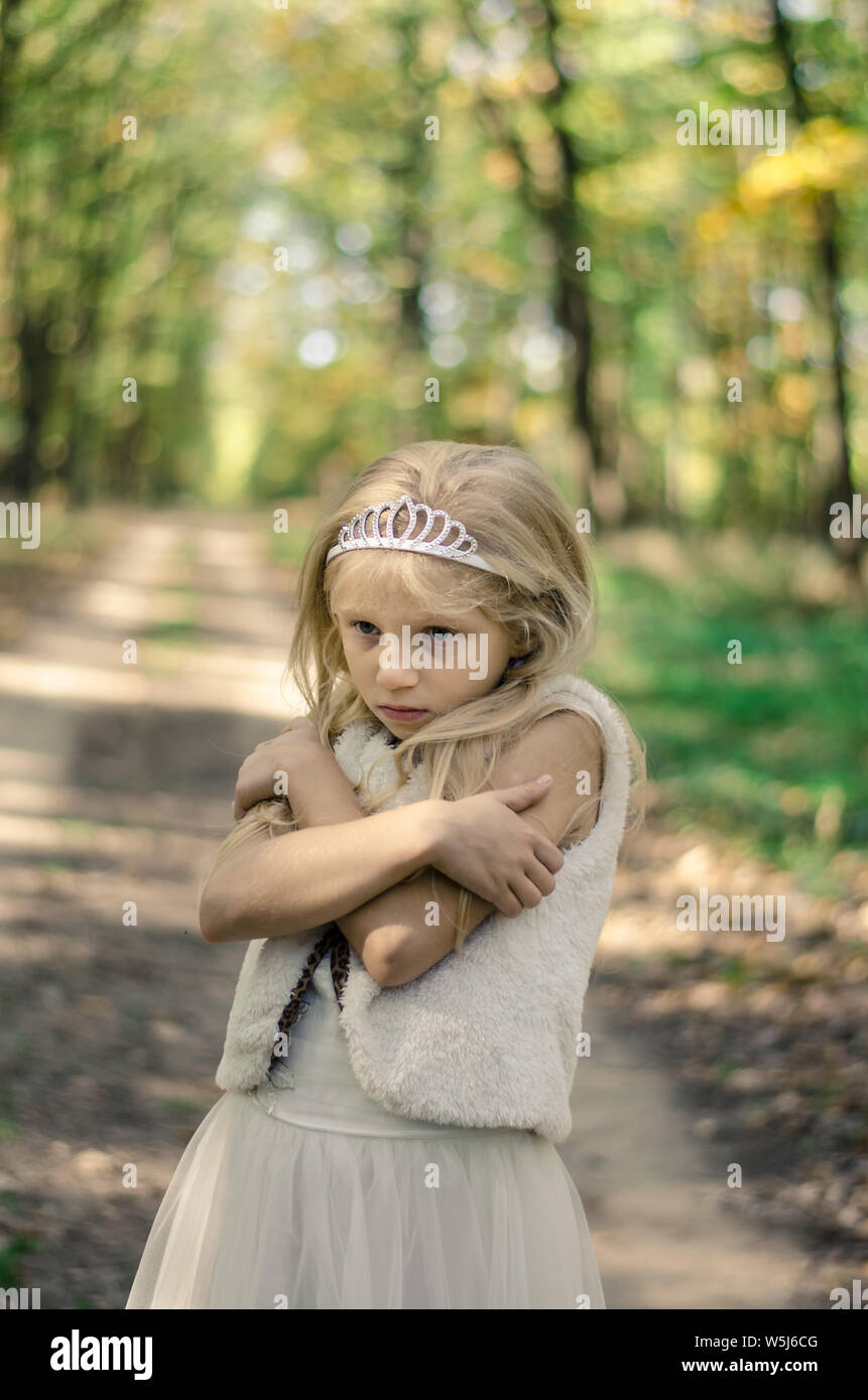 one little girl in dress freezing in path among autumnal trees in ...