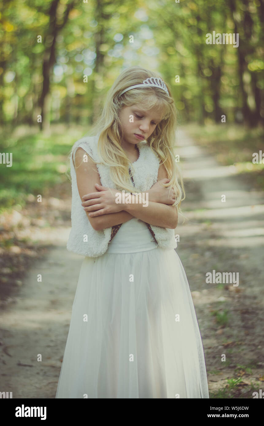 one little girl in dress freezing in path among autumnal trees in ...