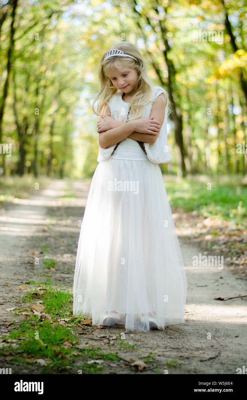 one little girl in dress freezing in path among autumnal trees in ...