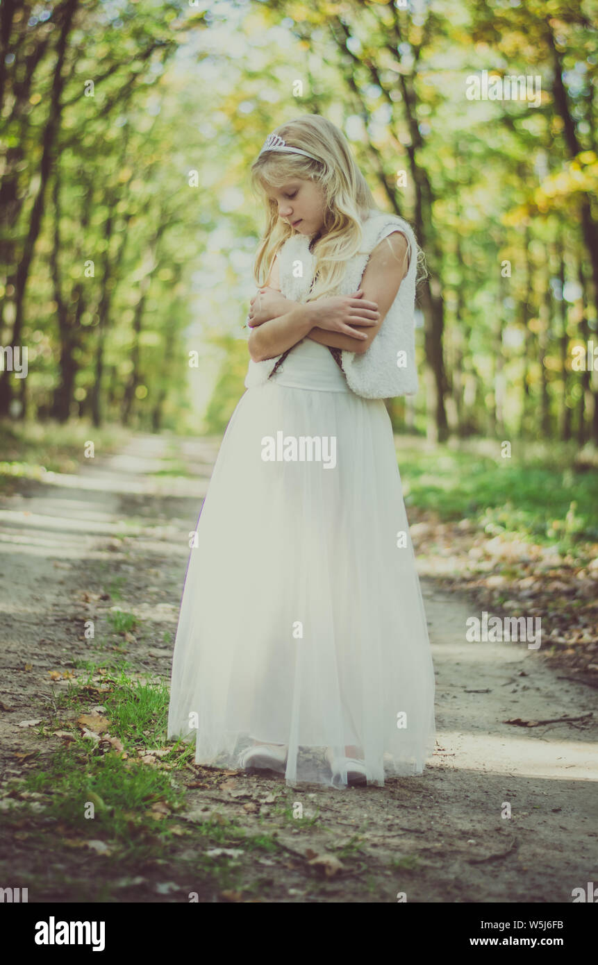 one little girl in dress freezing in path among autumnal trees in ...