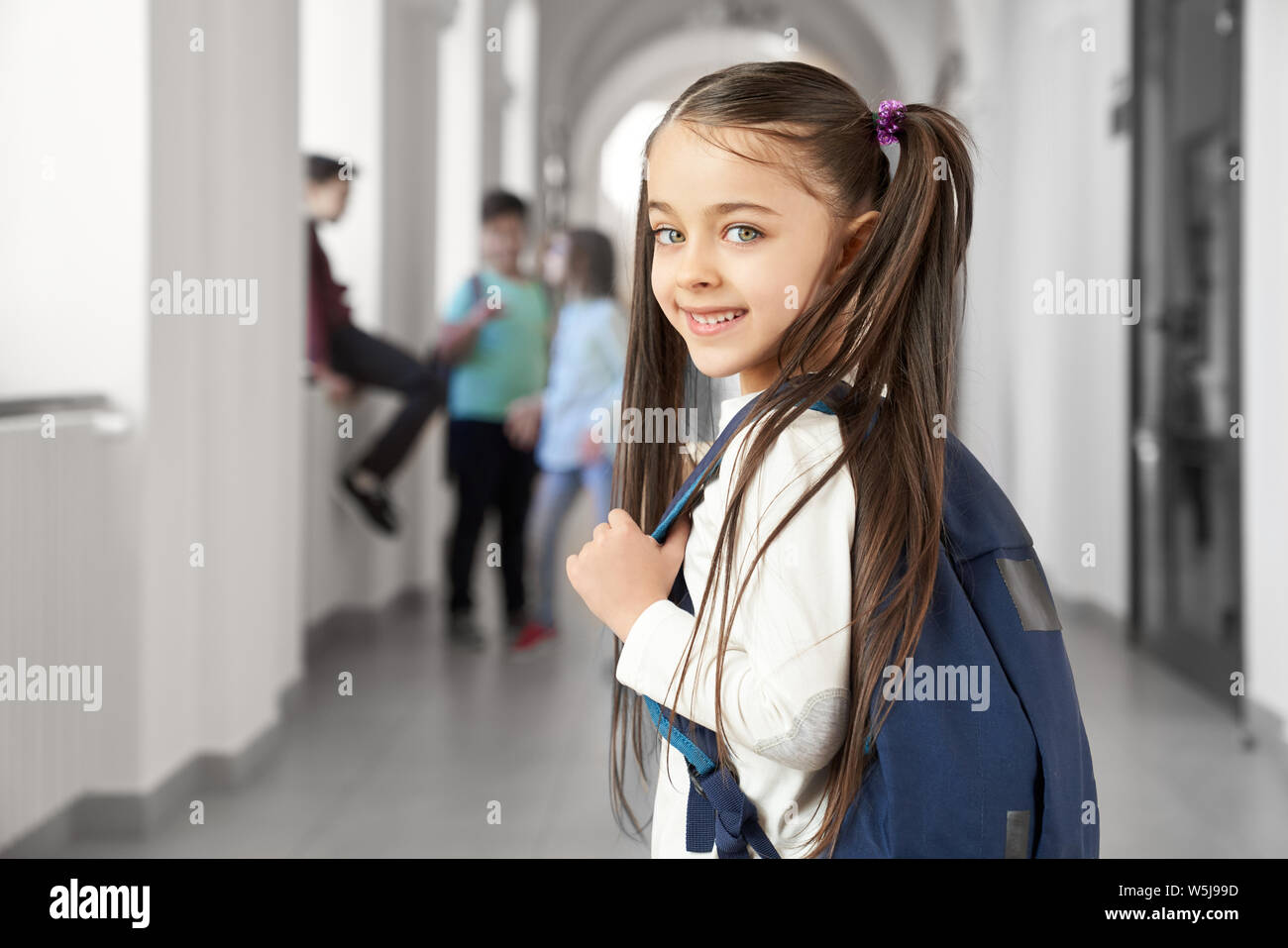 Pretty little girl with funny hairstyle looking over shoulder at camera ...