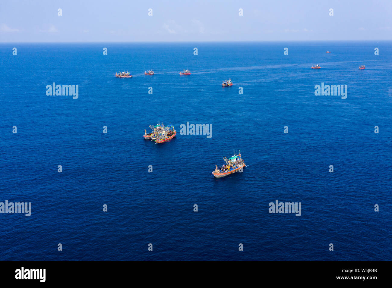 Overfishing - aerial view of a large fleet of fishing trawlers working ...