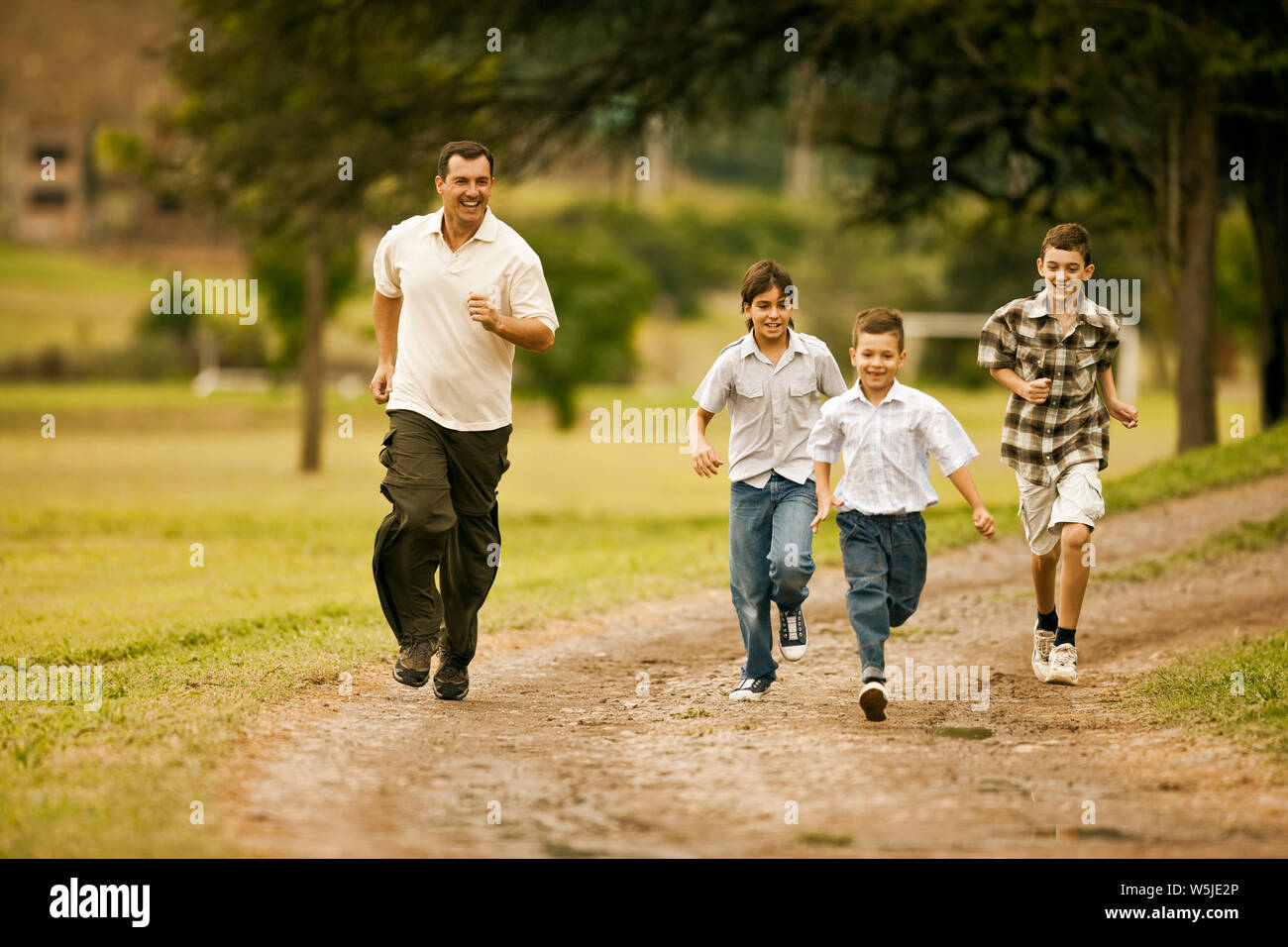 Three boys running with their father Stock Photo - Alamy