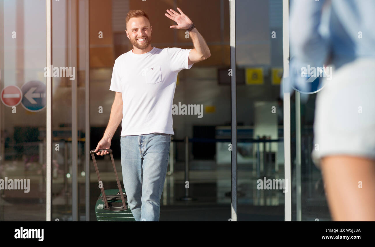 Young man greeting friend, arriving at airport Stock Photo - Alamy