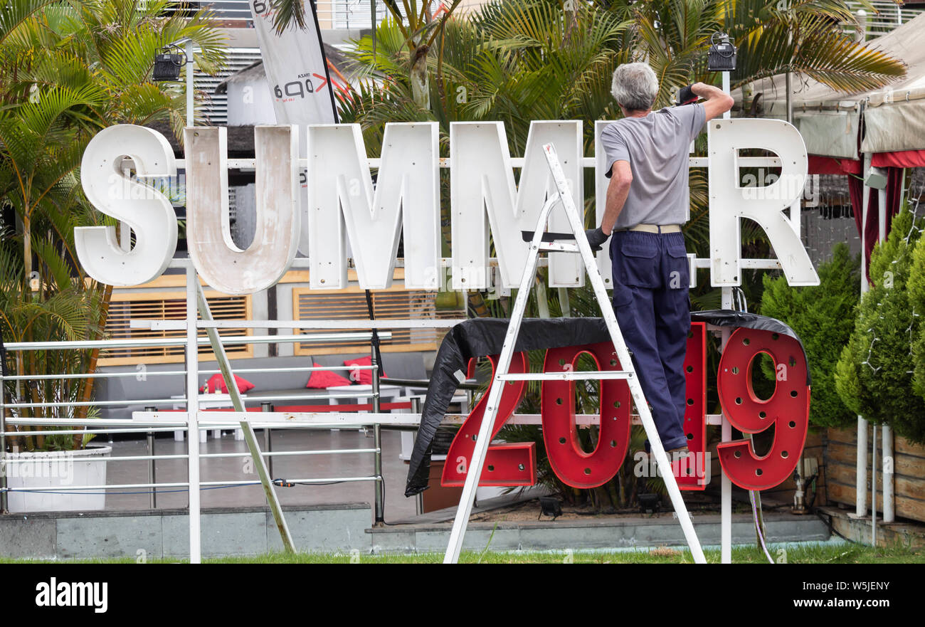 Worker painting summer 2019 sign Stock Photo - Alamy