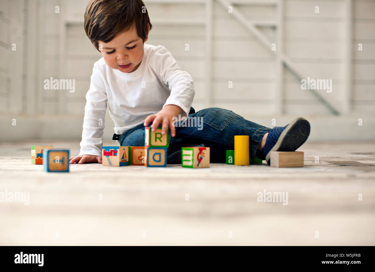 Toddler boy playing with blocks on the floor Stock Photo - Alamy