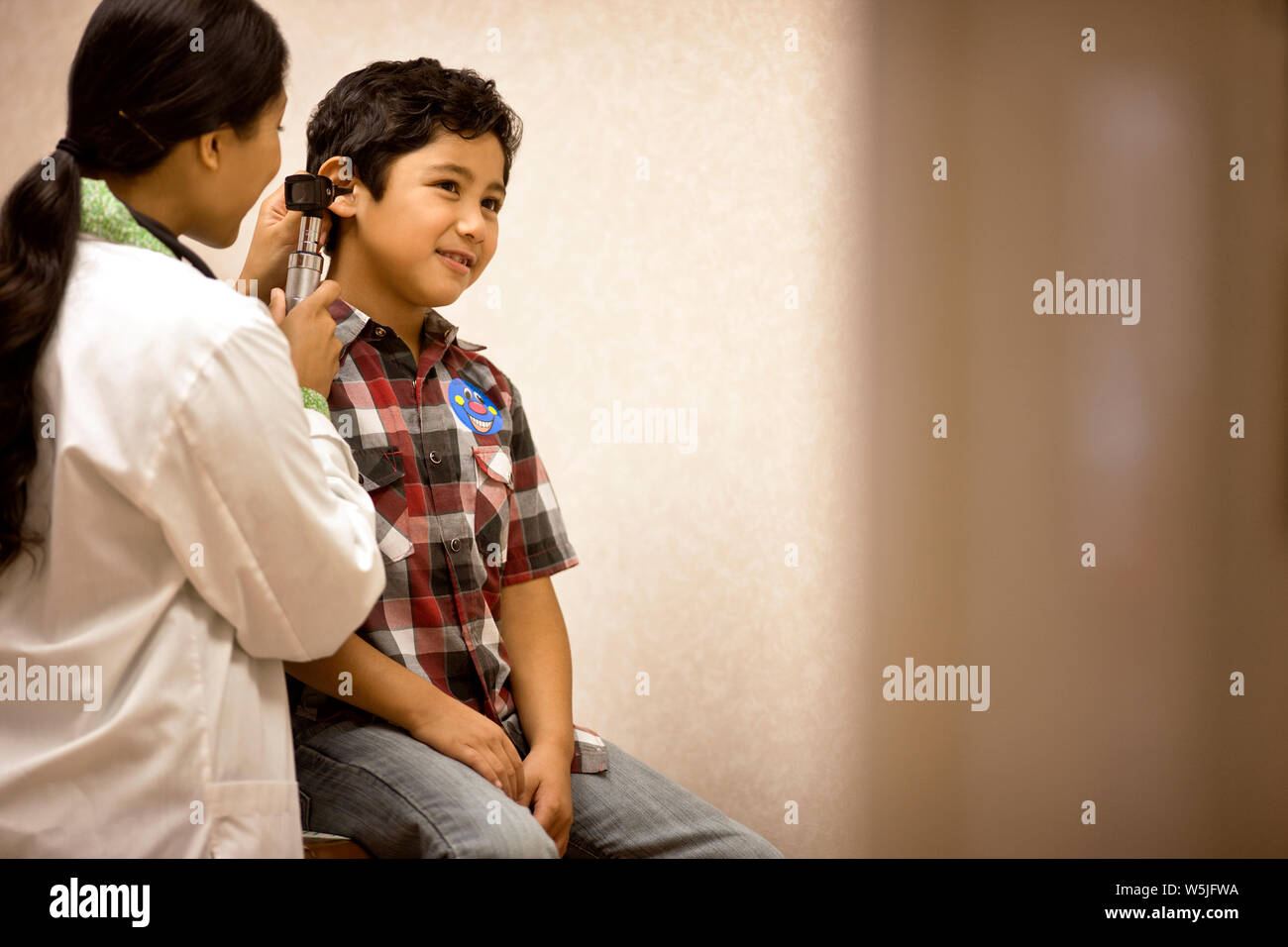 Doctor examining boy's ear with otoscope Stock Photo - Alamy