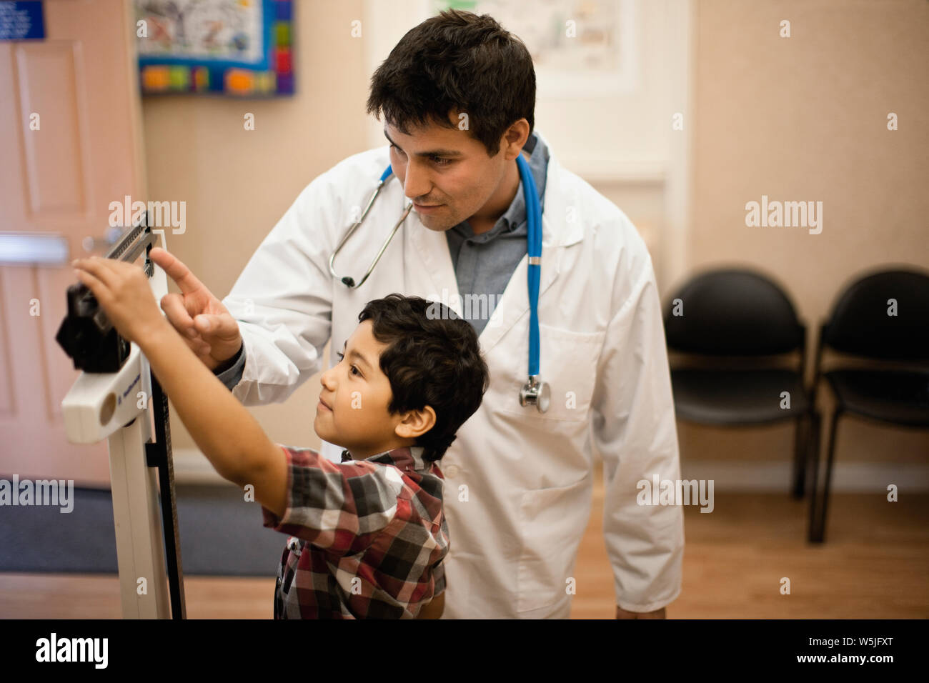 Doctor measuring young patient's weight on medical scales Stock Photo ...
