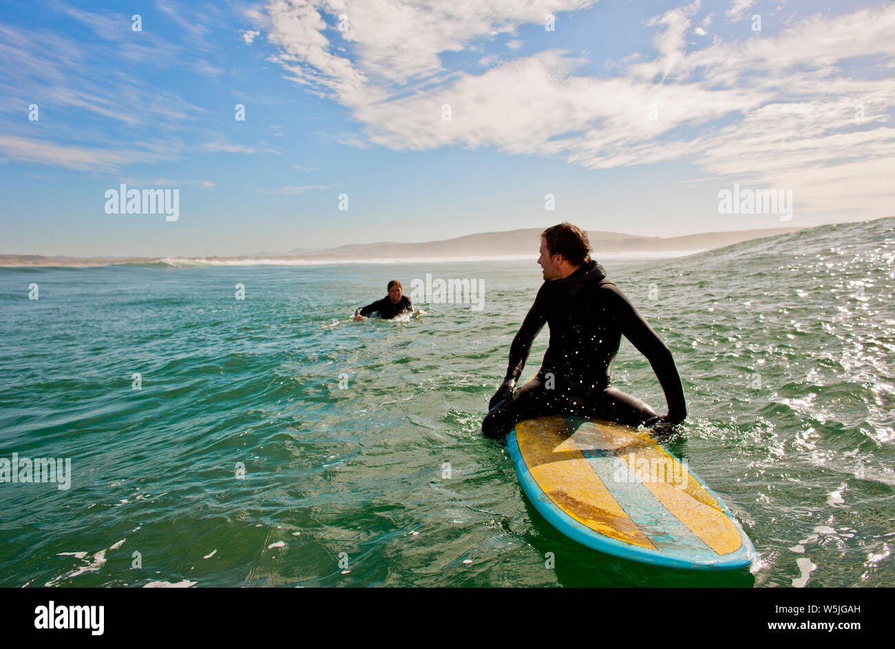Two surfers heading out to catch some waves Stock Photo - Alamy