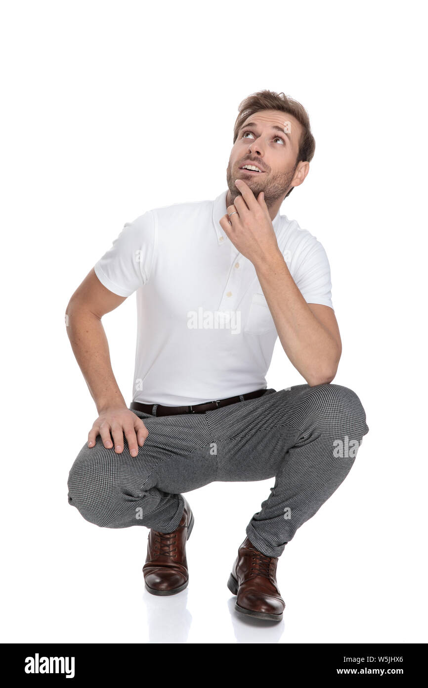 smiling crouched casual man looks up and wonders what is it over there ...