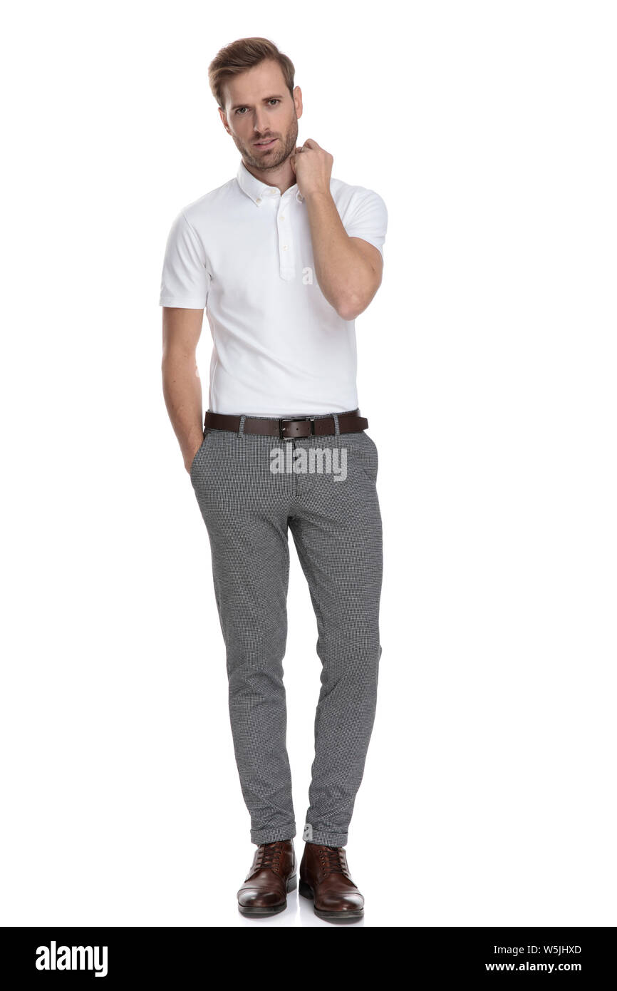 full body picture of a young casual man fixing his collar while ...