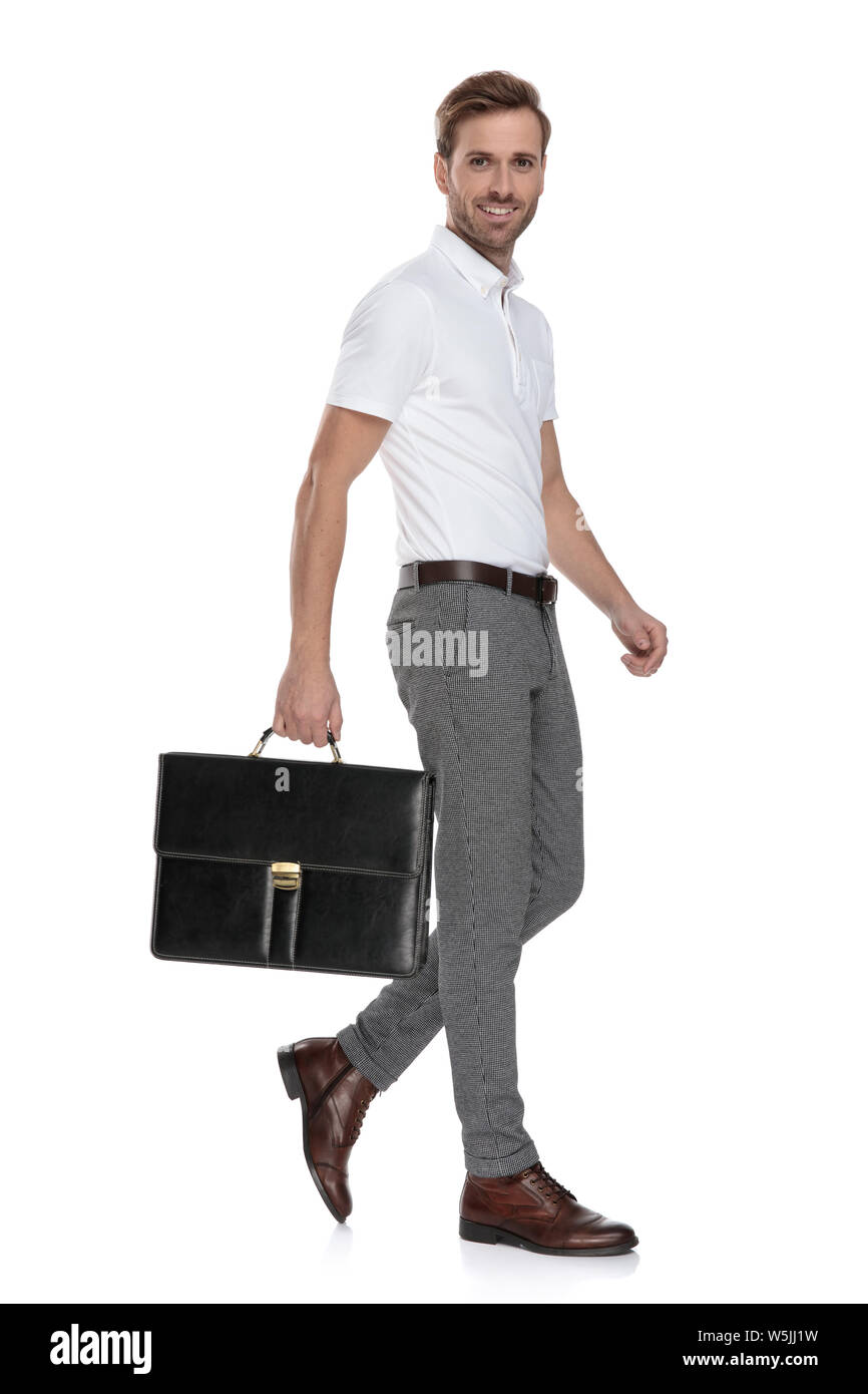 side view of a happy smart casual man holding case is stepping forward ...