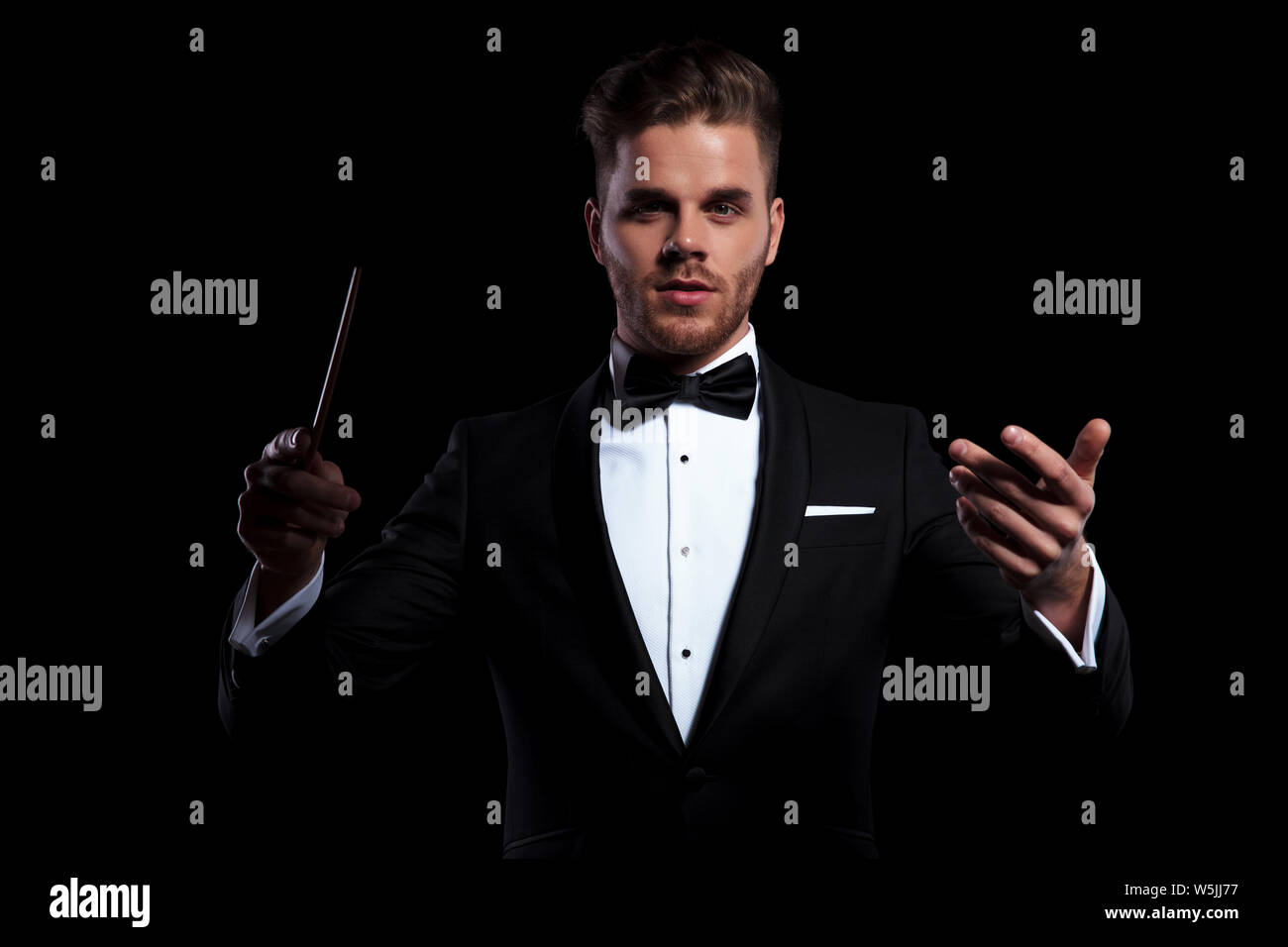 front view of young musician conducting using a stick and gesturing on ...