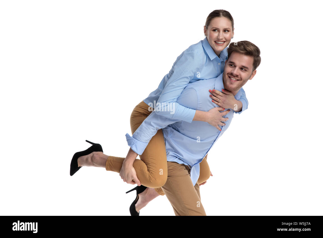 side view of a couple having fun, man carries woman on his back and ...