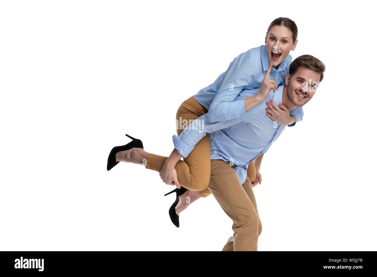 excited young casual woman on the back of her man , on white background ...