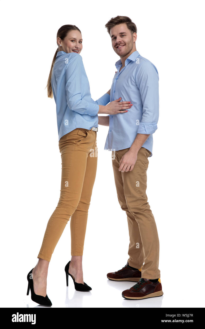 side view of a casual couple standing together on white background ...