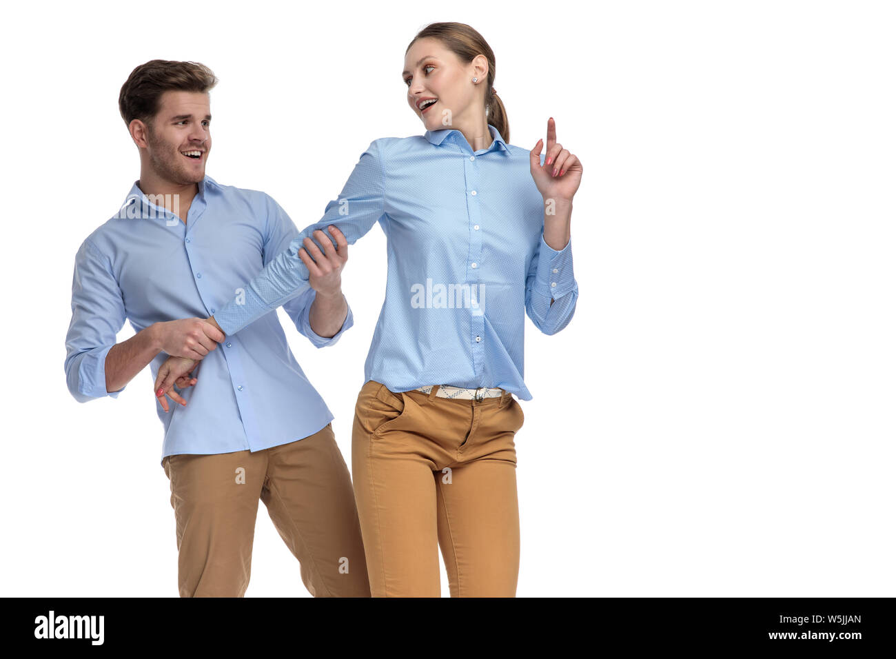 happy casual man pulling back his girlfriend by her arm on white ...