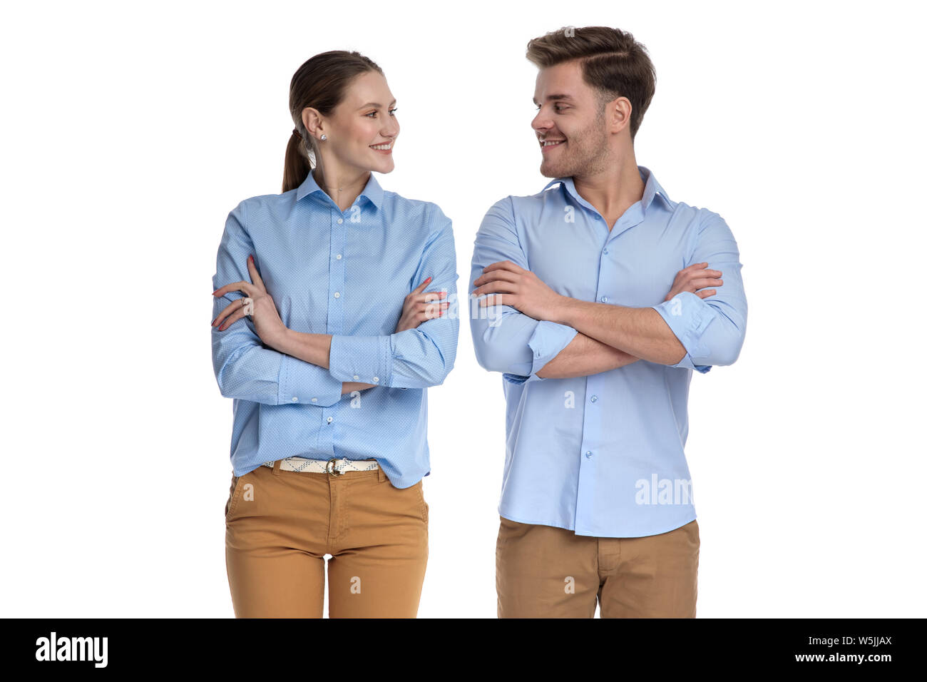 happy casual couple standing with hands crossed looking at each other ...