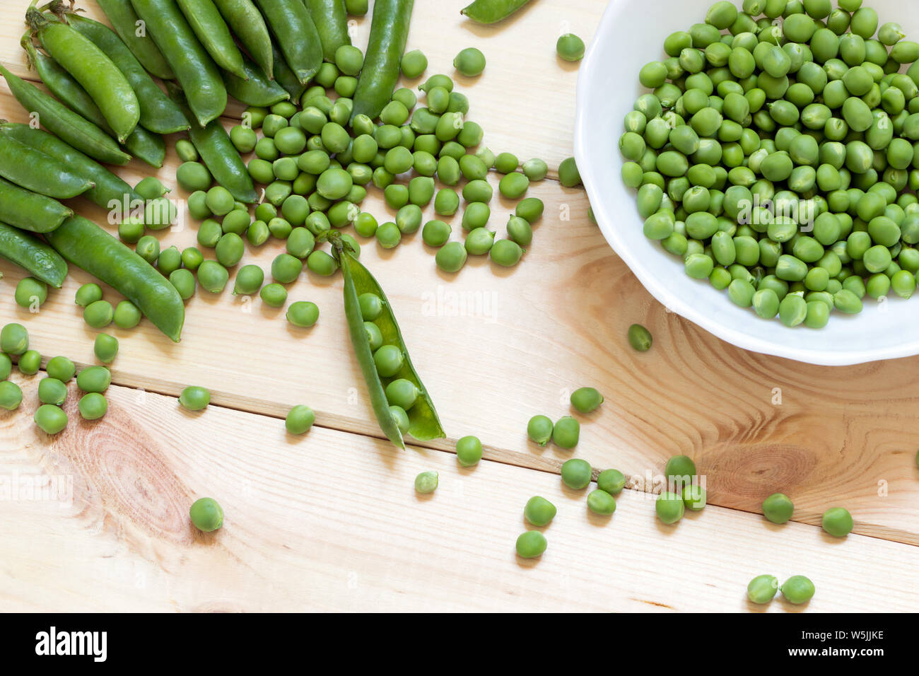 Background with freshness green peas scattered on the light wooden ...