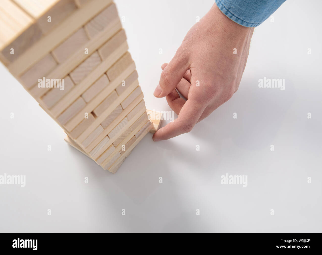 man playing jenga removes a brick from the base of the tower using only ...
