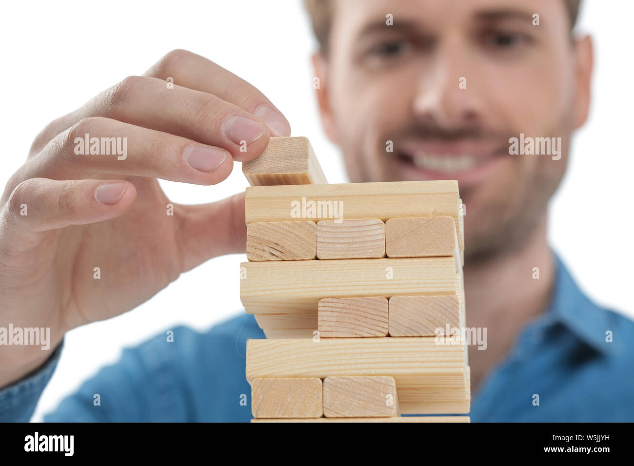 Casual dressed man puts the latest brick on top of the stack, feeling ...