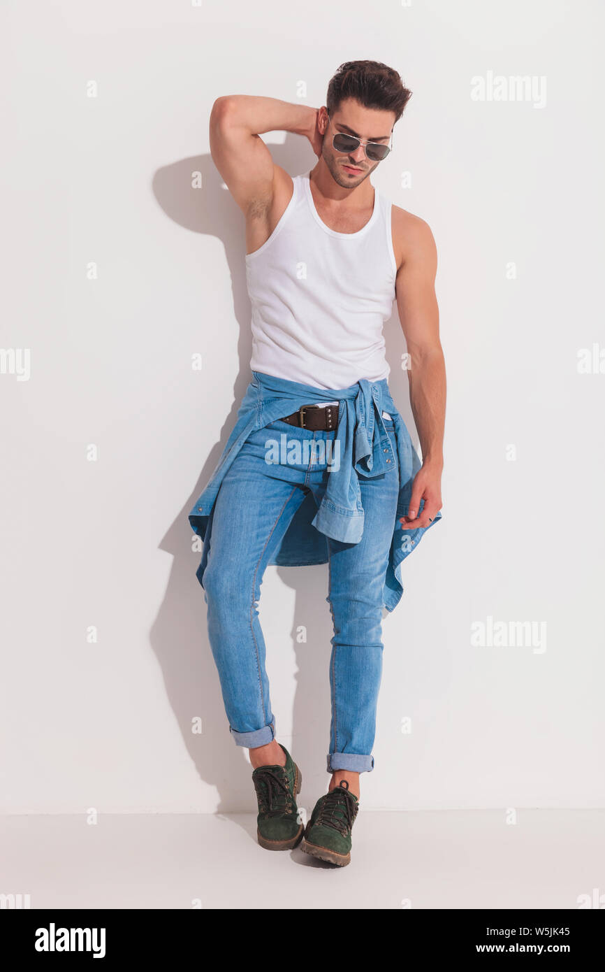 Attractive man posing with a hand behind his neck looking downwards on ...