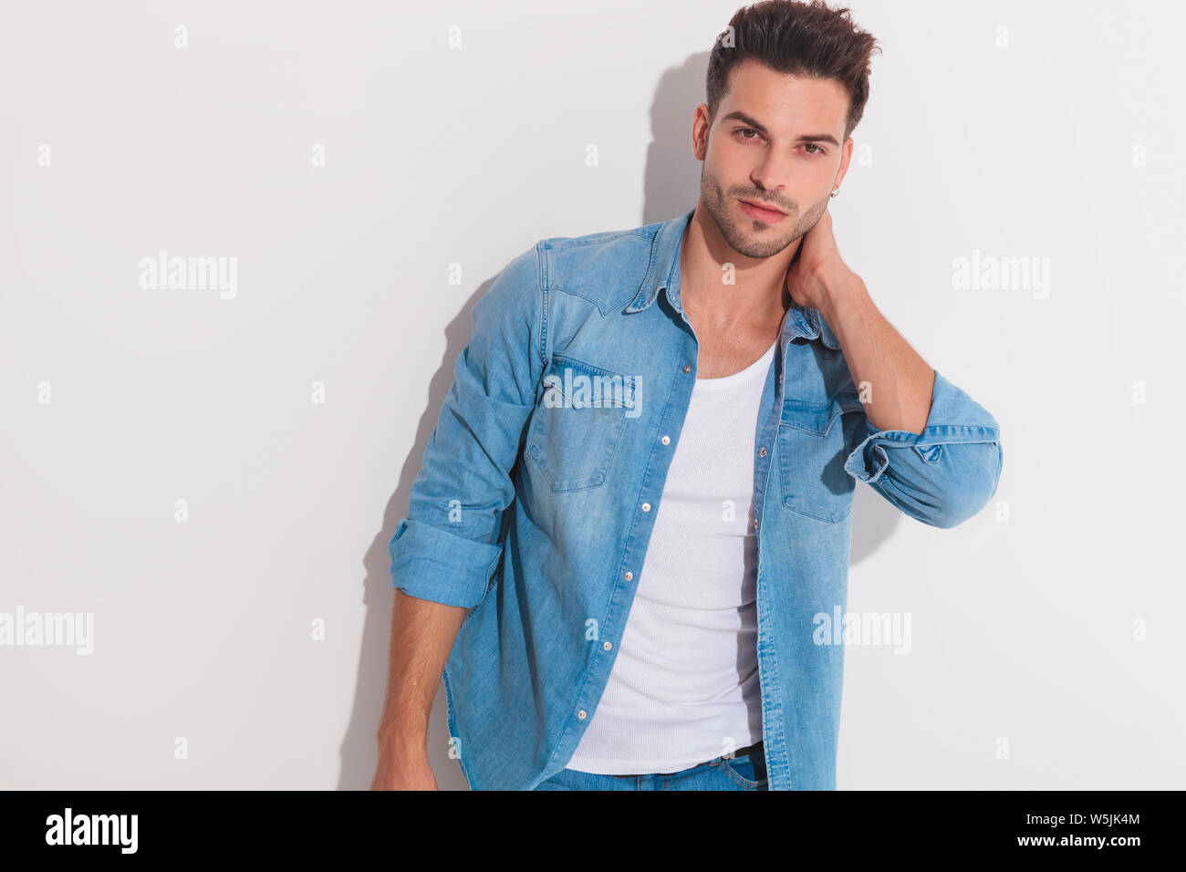 Attractive man smiling and holding a hand behind his neck while looking ...