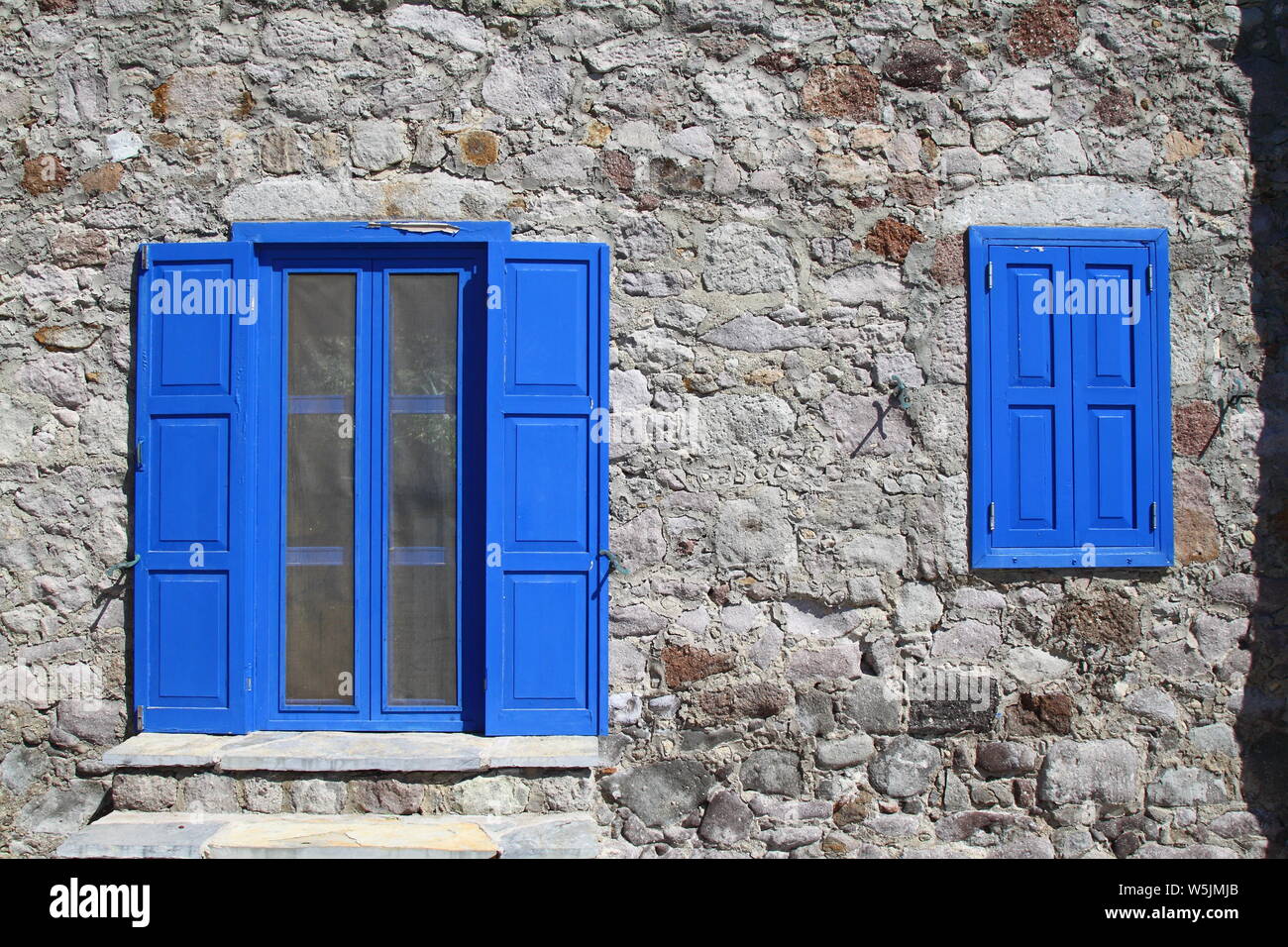 Open and closed light blue wooden window blinds on windows of newly ...