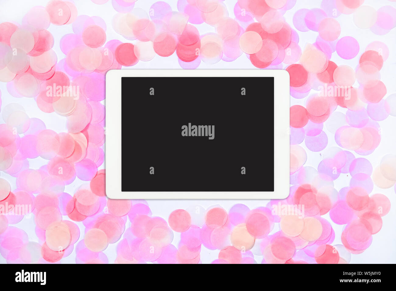 Touchpad with blank touchscreen with pink confetti background. Flat lay ...