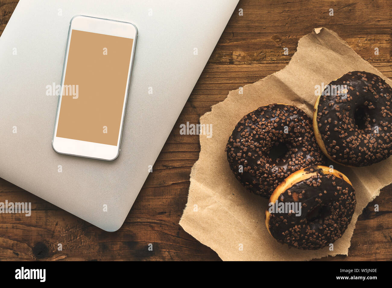 Smart phone mock up and chocolate doughnuts on table, top view of sweet ...