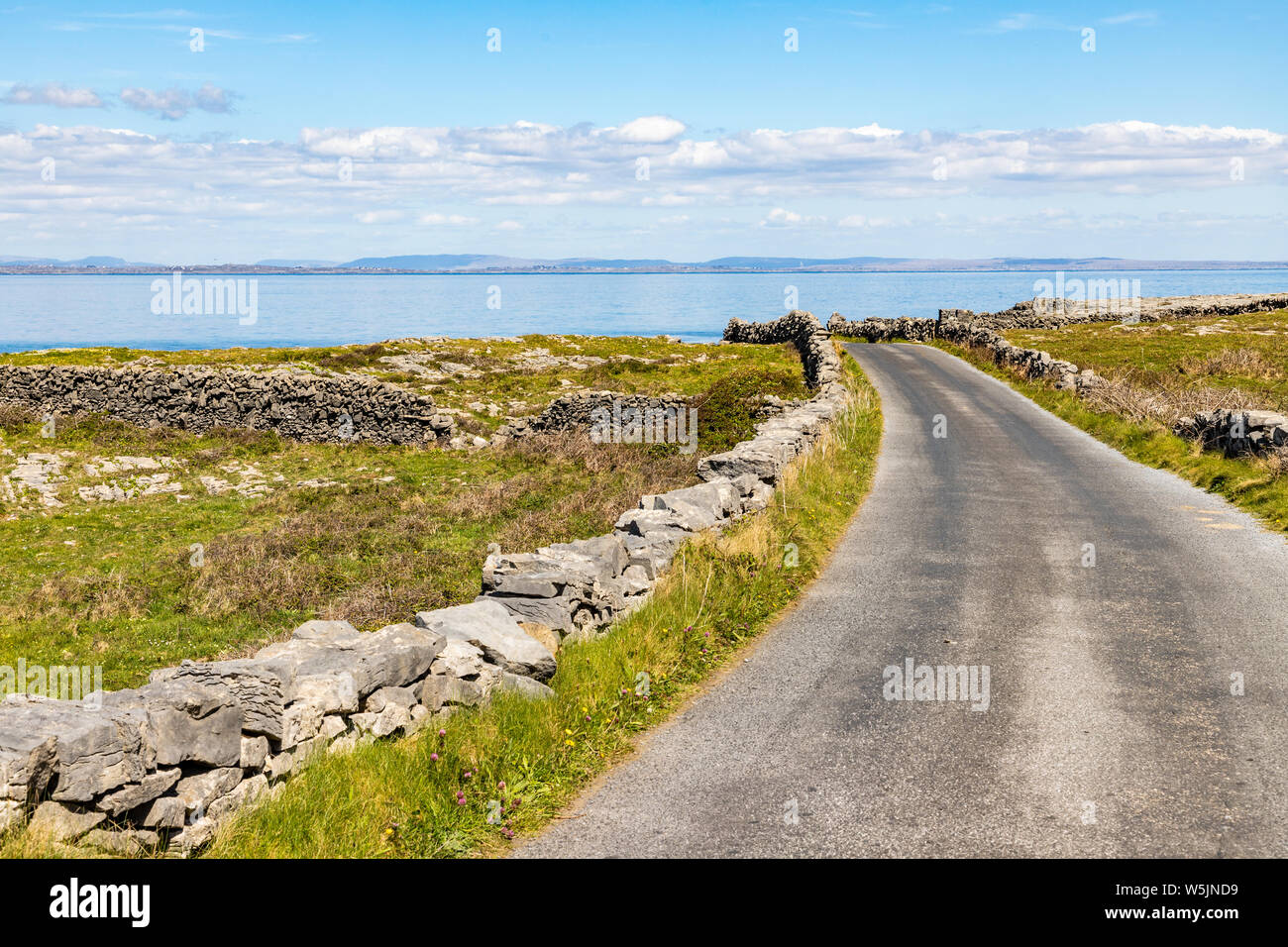 Farm road with rock walls and Galway bay in background in Inishmore ...