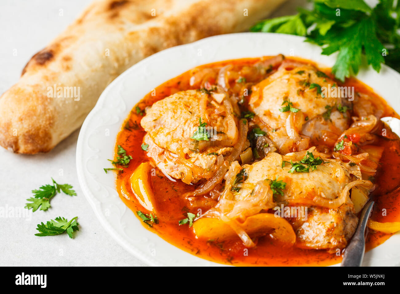Georgian traditional chicken chakhokhbili in a white plate, white ...