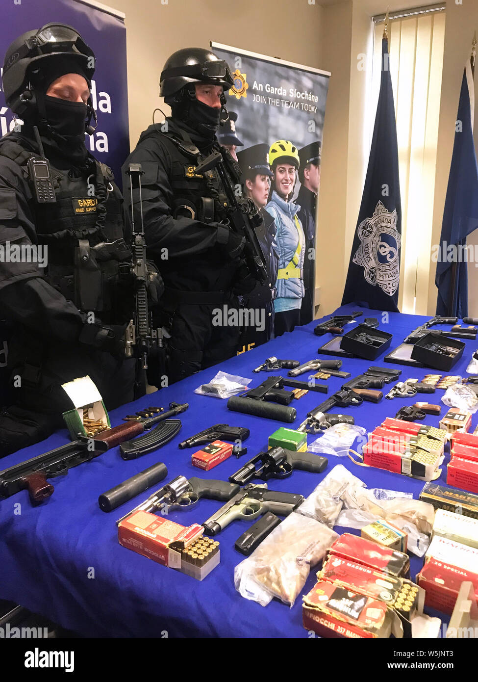 Two members garda emergency response unit stand over some firearms hi ...